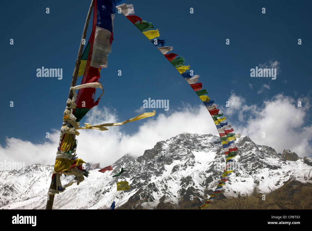 Colour photograph of prayer flags blowing in the wind at a mountain ...
