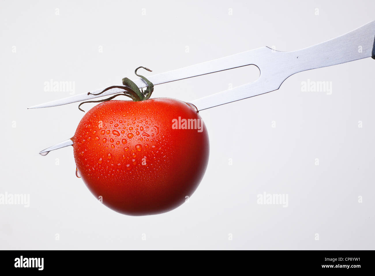 Tomato stabbed in fork against white background Stock Photo - Alamy