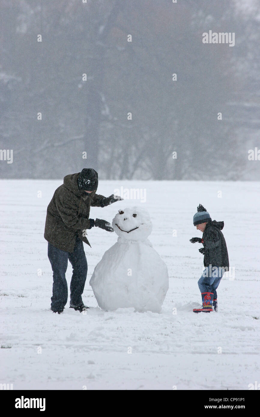 Adult and child making a snowman in Abington park Northampton UK Stock ...