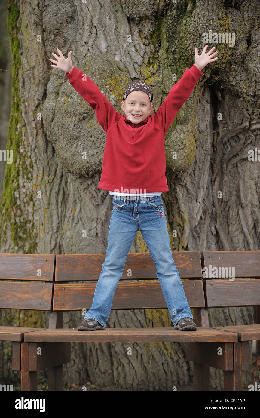 Germany, Bavaria, Girl standing on bench with arms up, portrait Stock ...