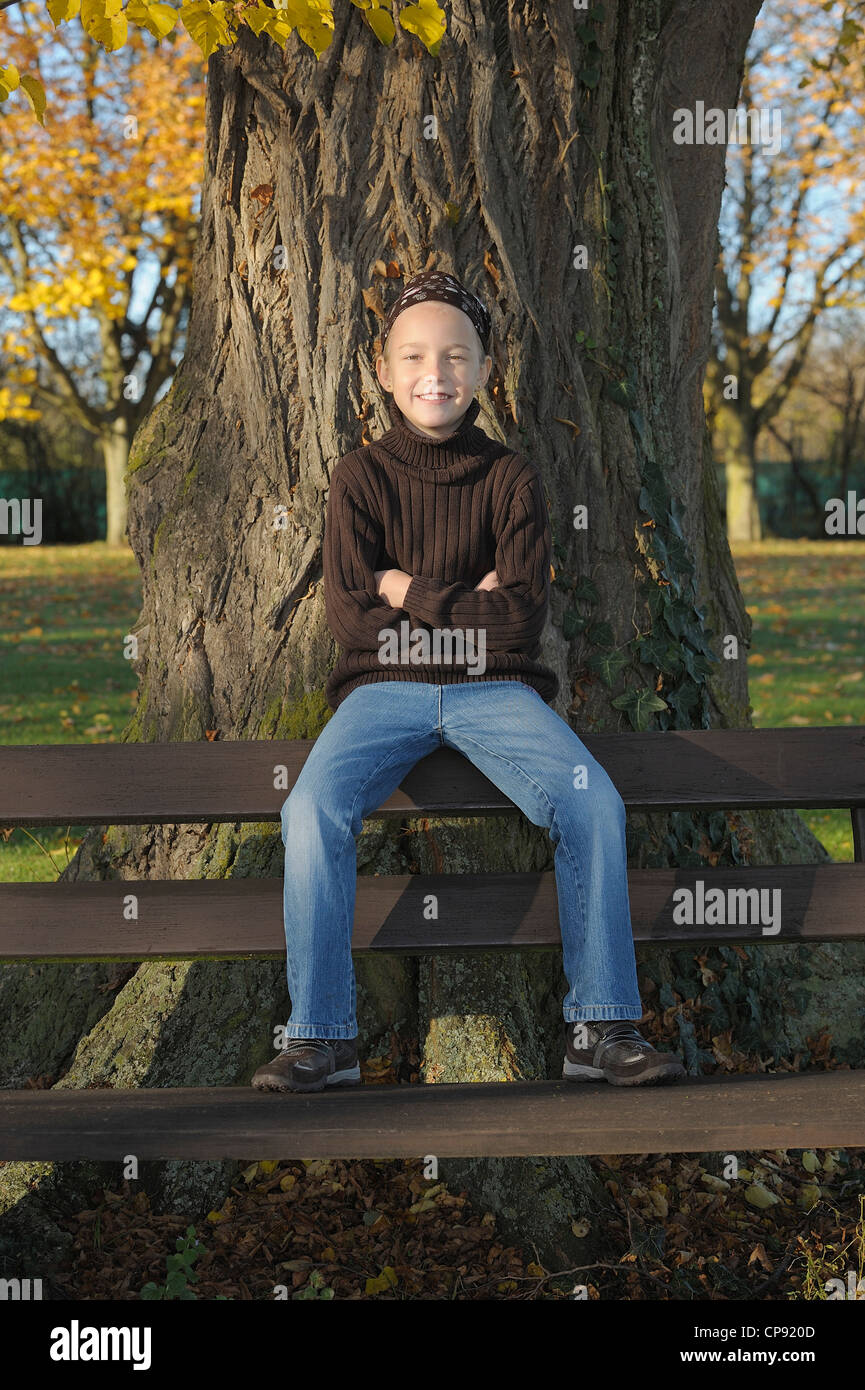 Germany, Bavaria, Girl sitting on bench with arms crossed, portrait ...
