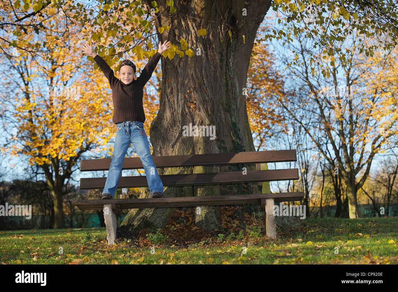 Germany, Bavaria, Girl standing on bench with arms up, portrait Stock ...
