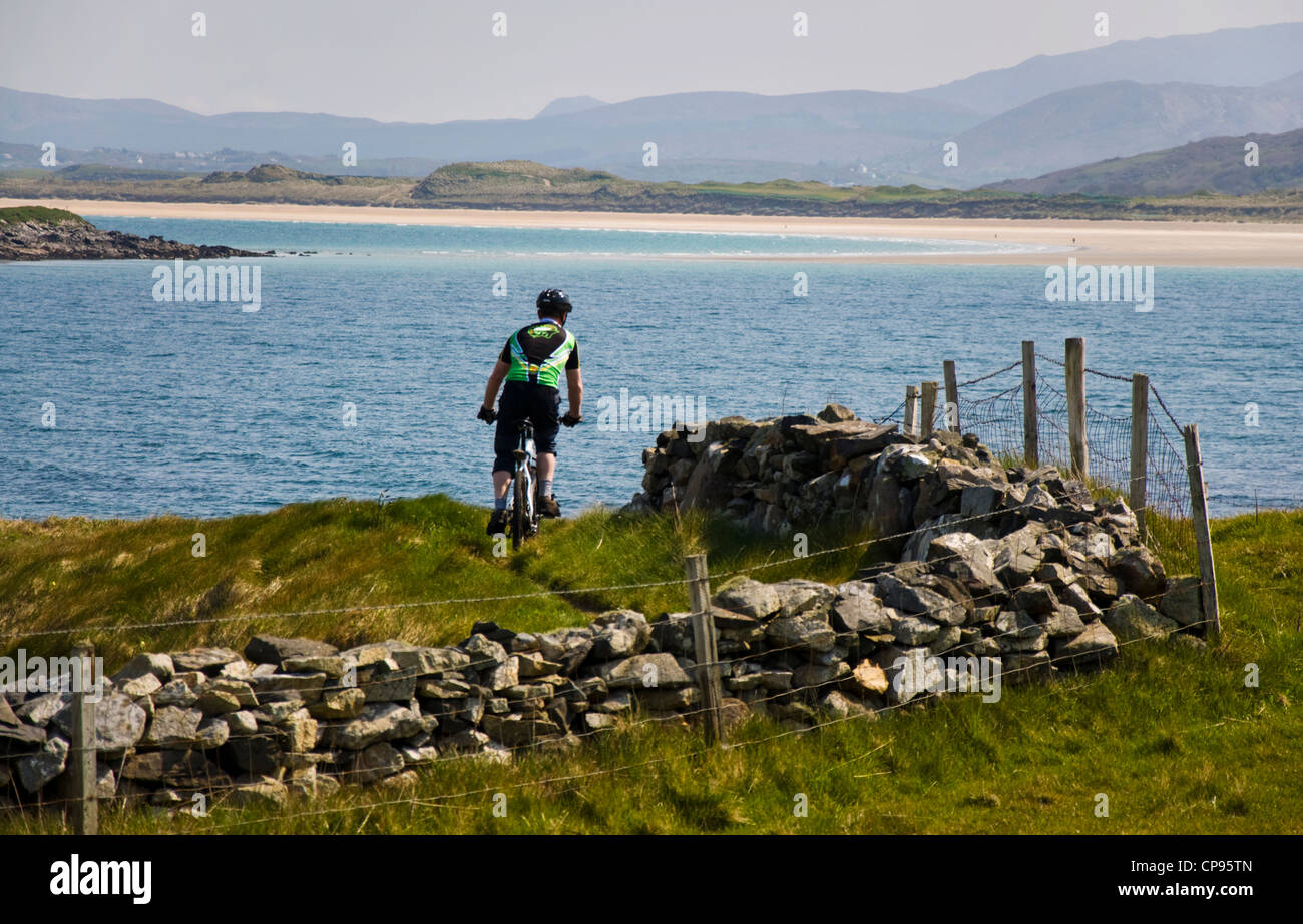 Man on mountain bike cycles by Atlantic Ocean coastline in Donegal ...