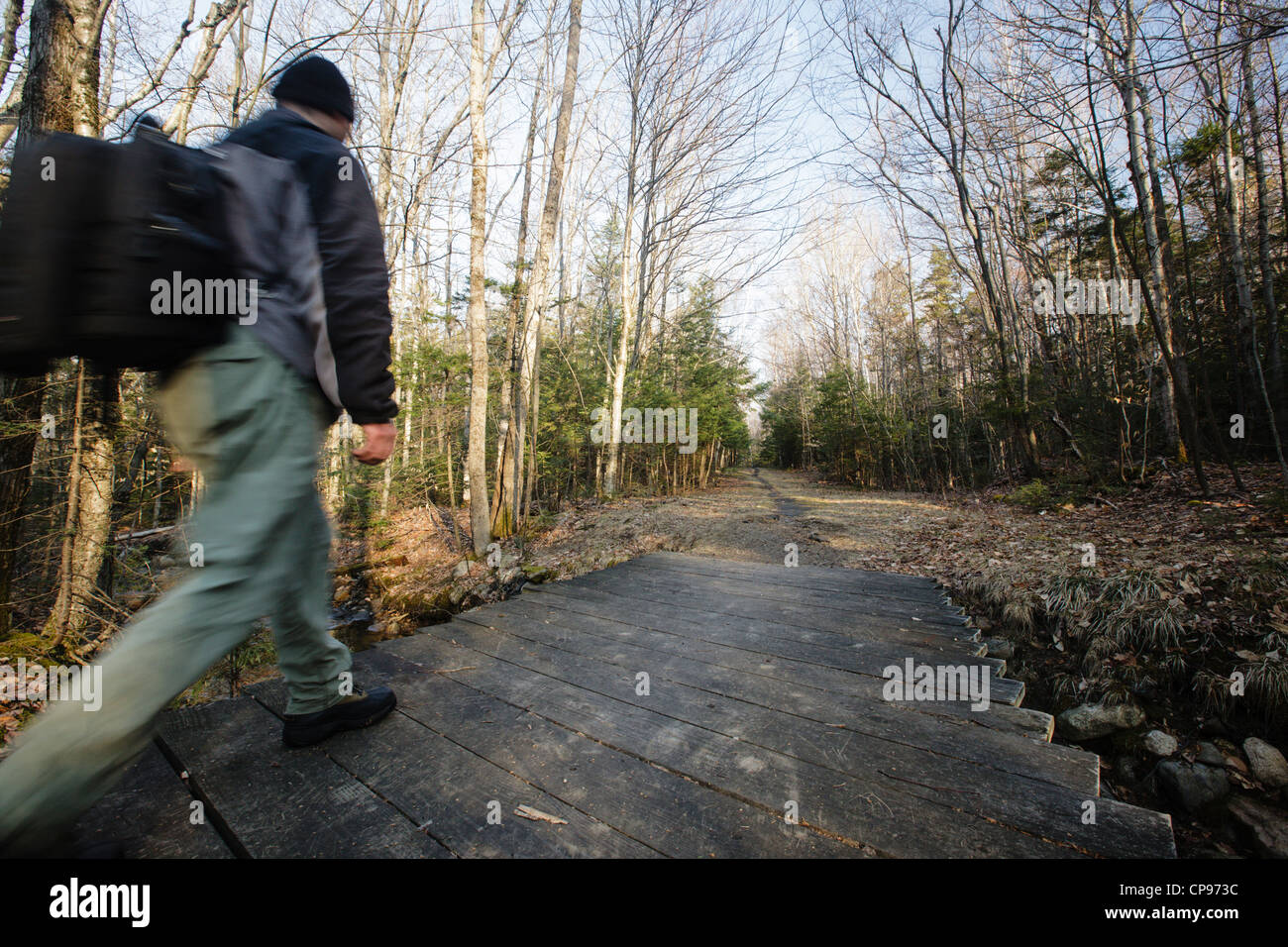 Hiker on trail crossing wooden bridge Stock Photo - Alamy