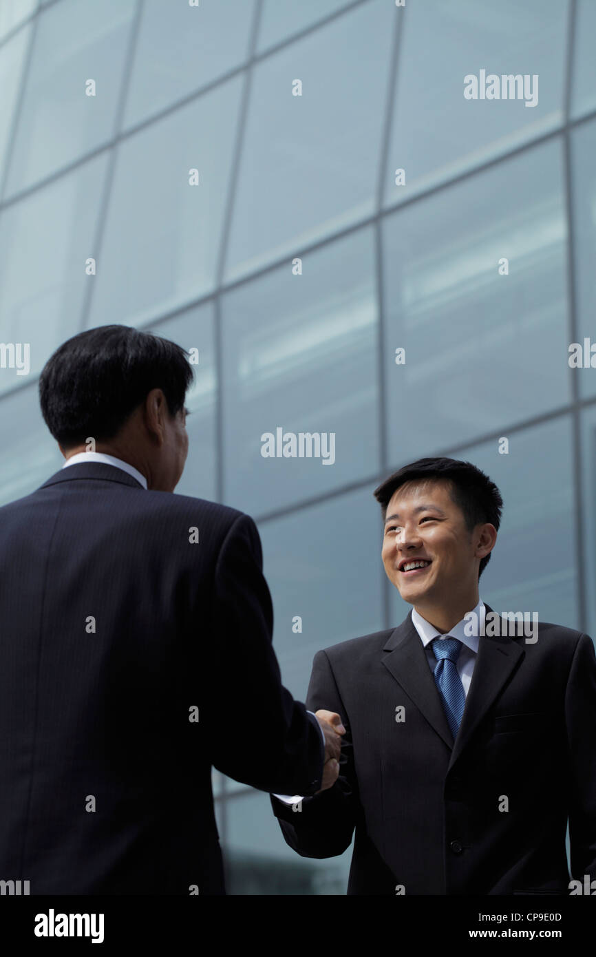 Businessmen shaking hands in front of a building Stock Photo - Alamy