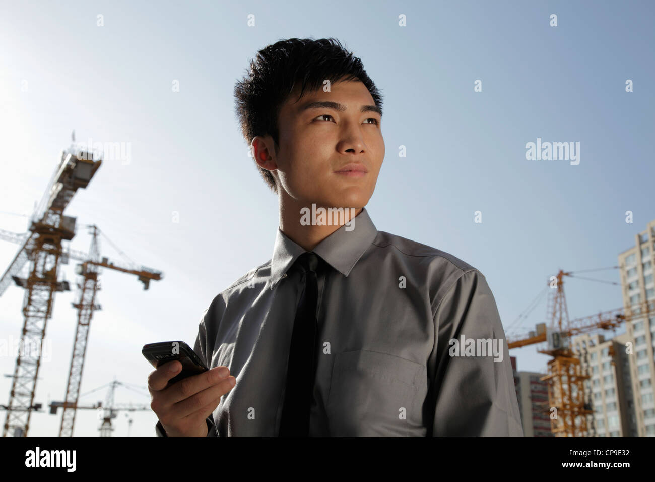 Young man holding phone, construction background Stock Photo - Alamy