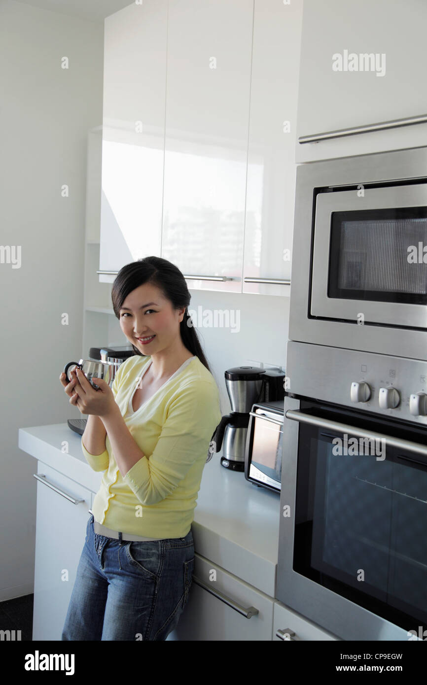 Woman leaning against kitchen counter Stock Photo - Alamy