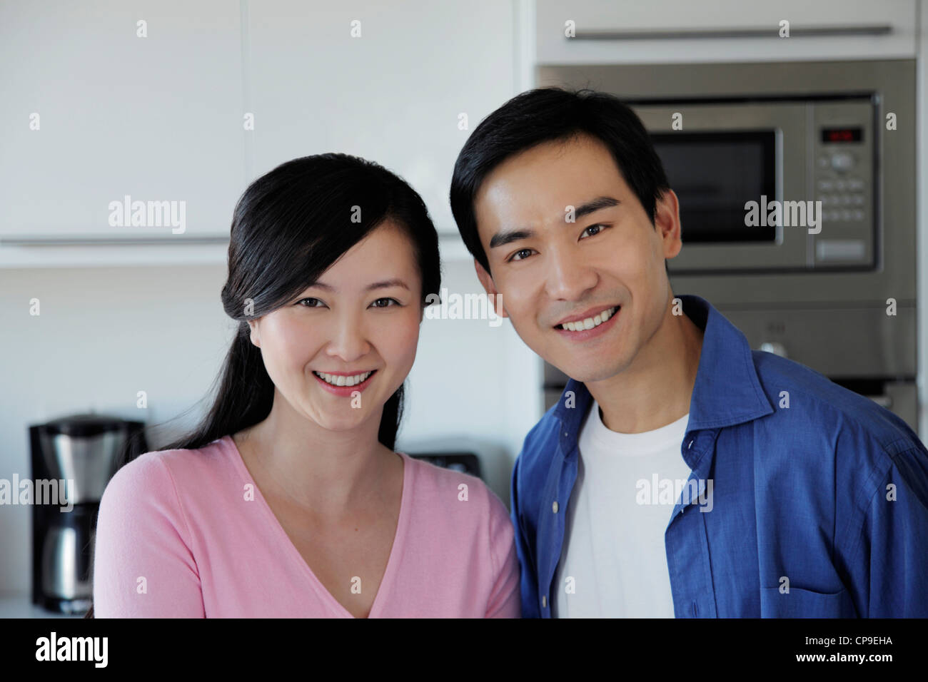 Couple smiling together in kitchen Stock Photo - Alamy