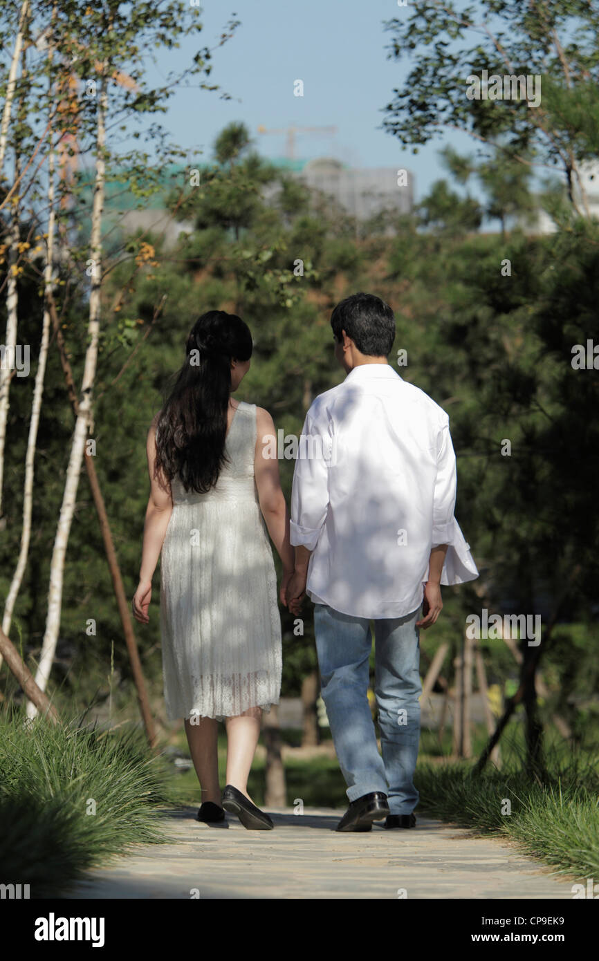 Rear view of young couple walking down a path Stock Photo - Alamy