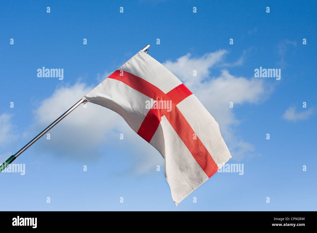 Slighted tattered English flag hanging from mast against blue sky Stock ...