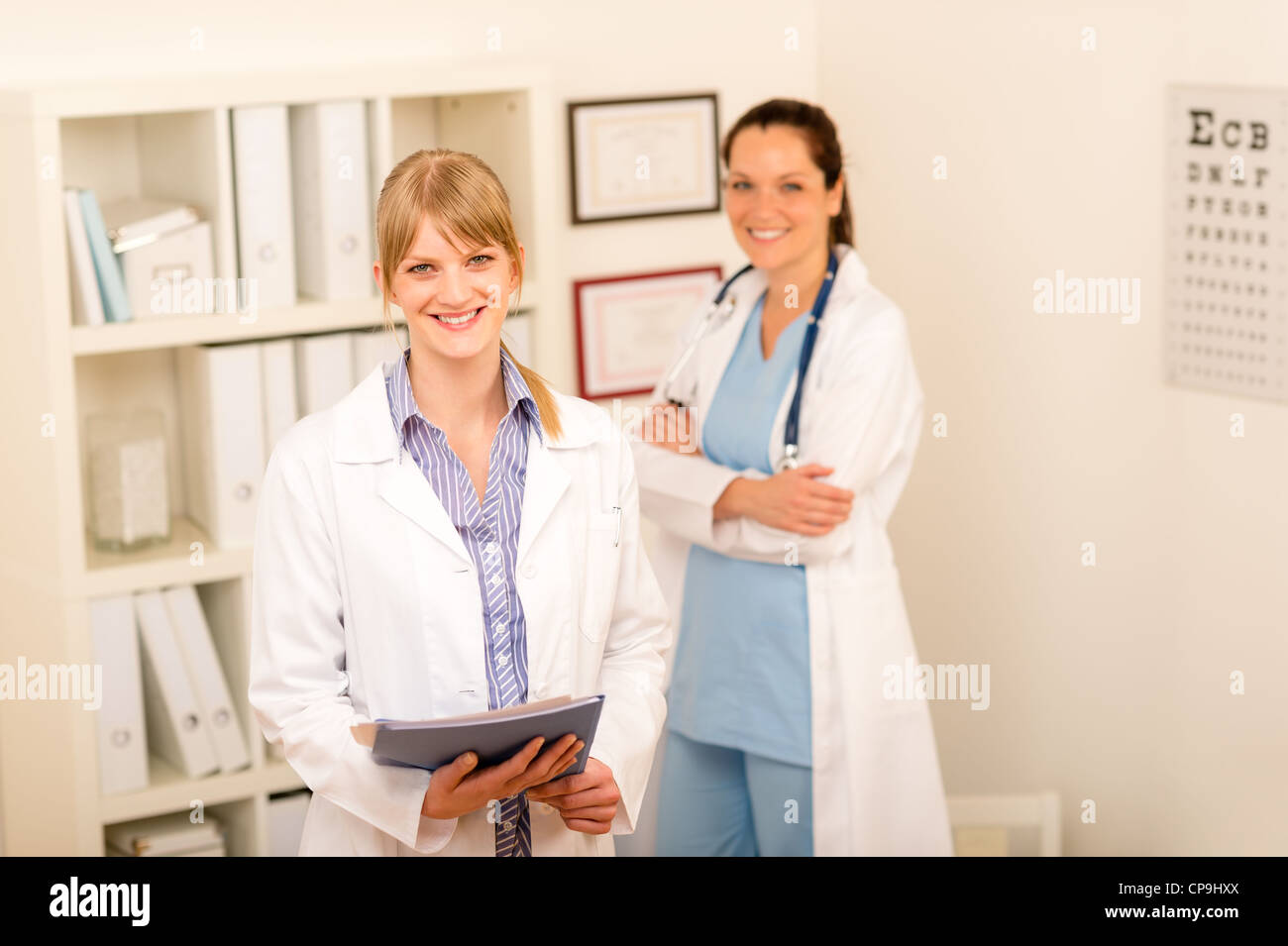 Portrait of two female doctors standing at medical office together ...