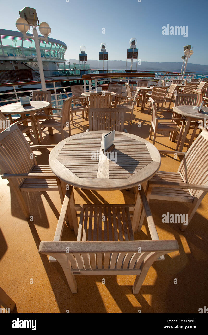 The seating area on the deck of a luxury cruise ship, with tables and ...