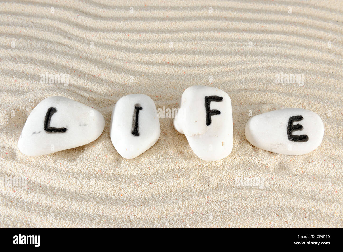 Life word on group of stones with sand as background Stock Photo - Alamy