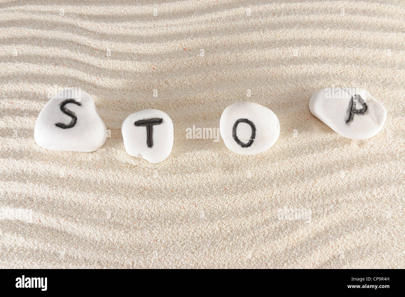 Stop word on group of stones with sand as background Stock Photo - Alamy