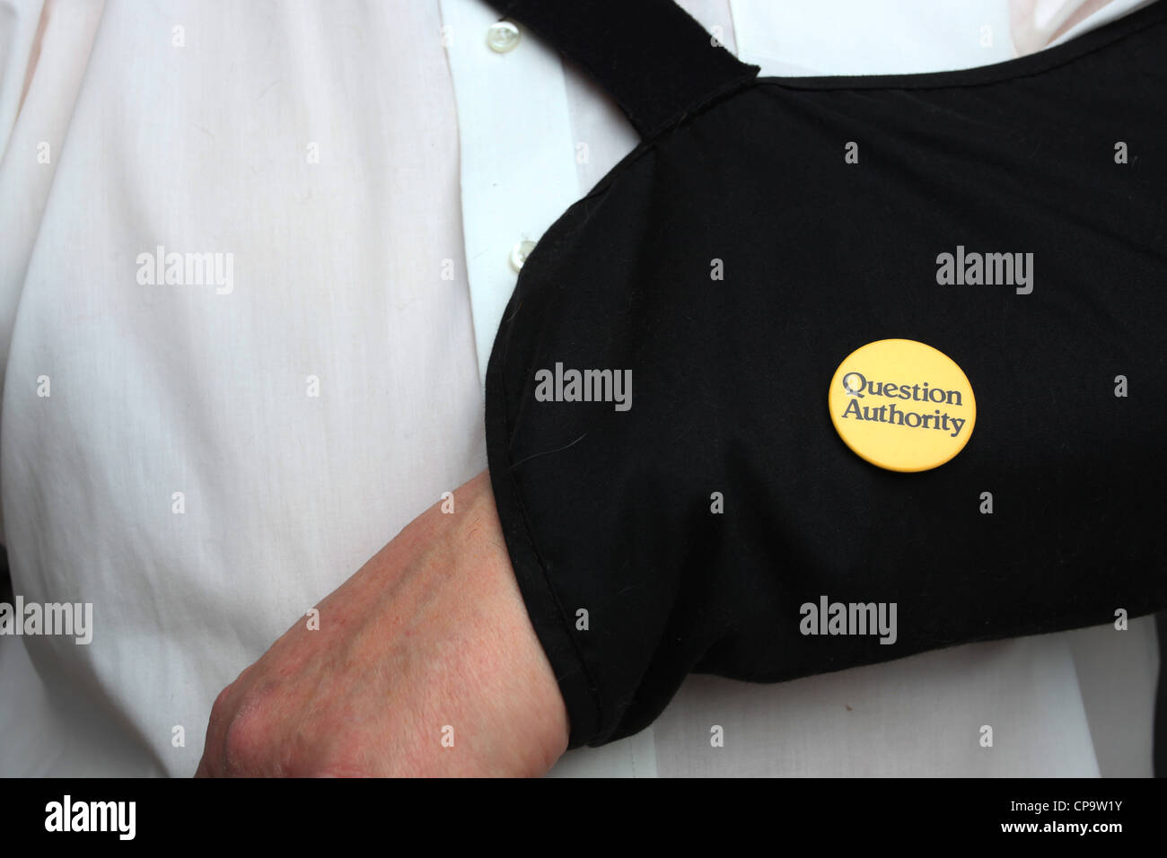 Question authority pin worn on black arm sling Stock Photo - Alamy