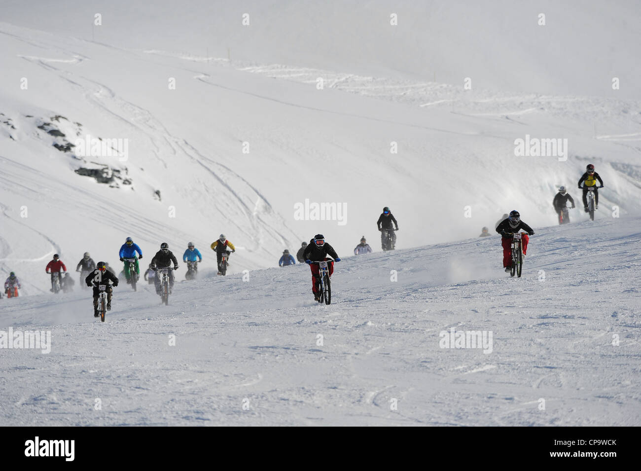 Downhill mountain bikers race at speed on snow during the Saas Fee ...