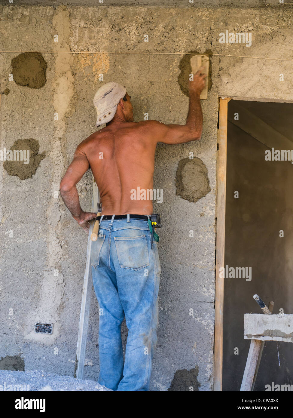 A Cuban construction worker applies new stucco to the front of a ...
