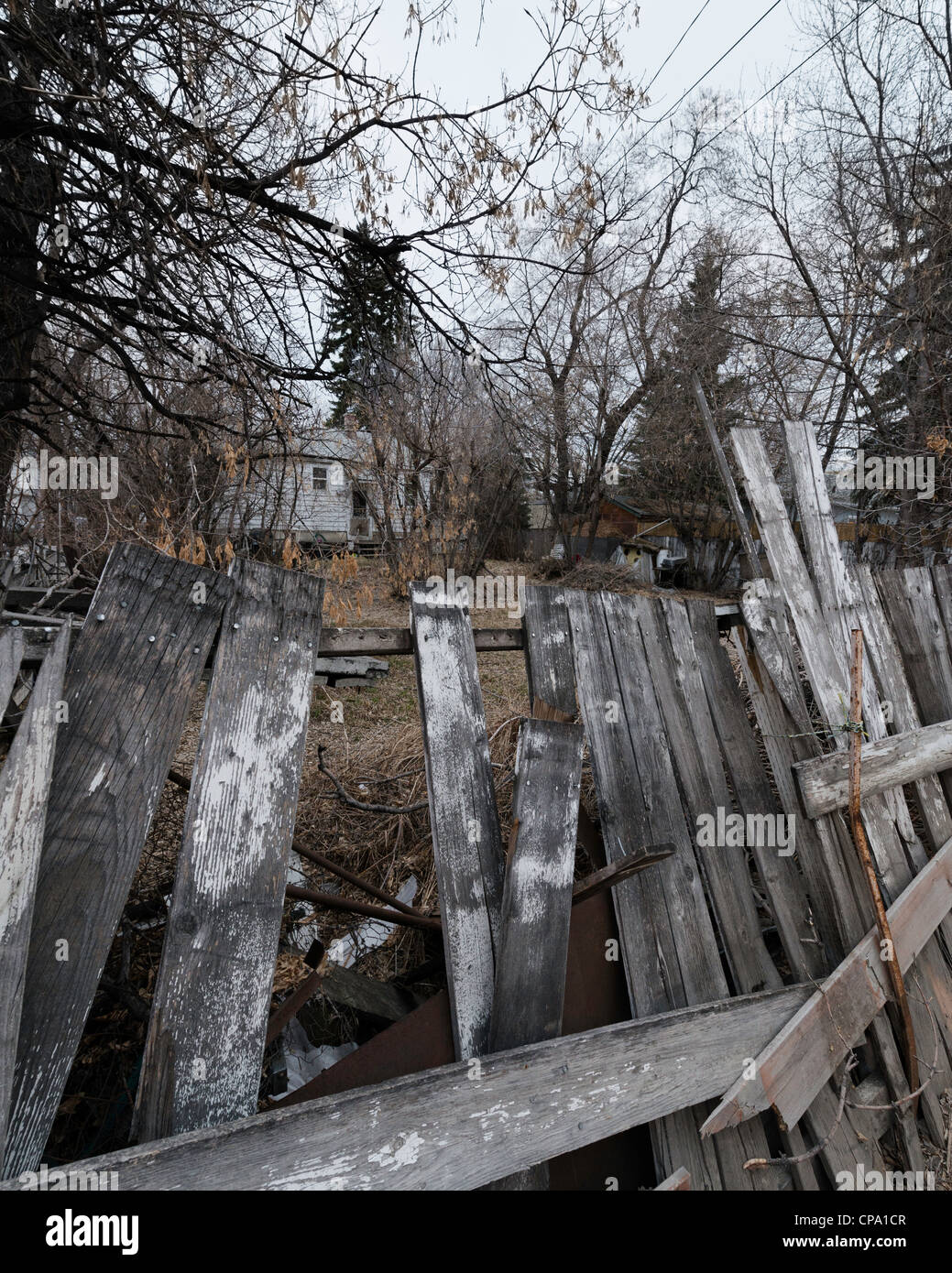 An abandoned home in disrepair. The fence is dramatically in the ...