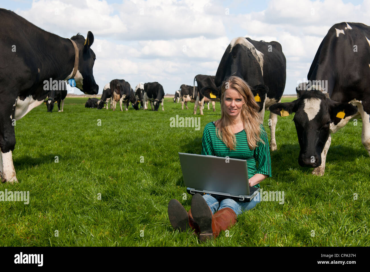Young blond Dutch girl in farm field with laptop and black and white ...