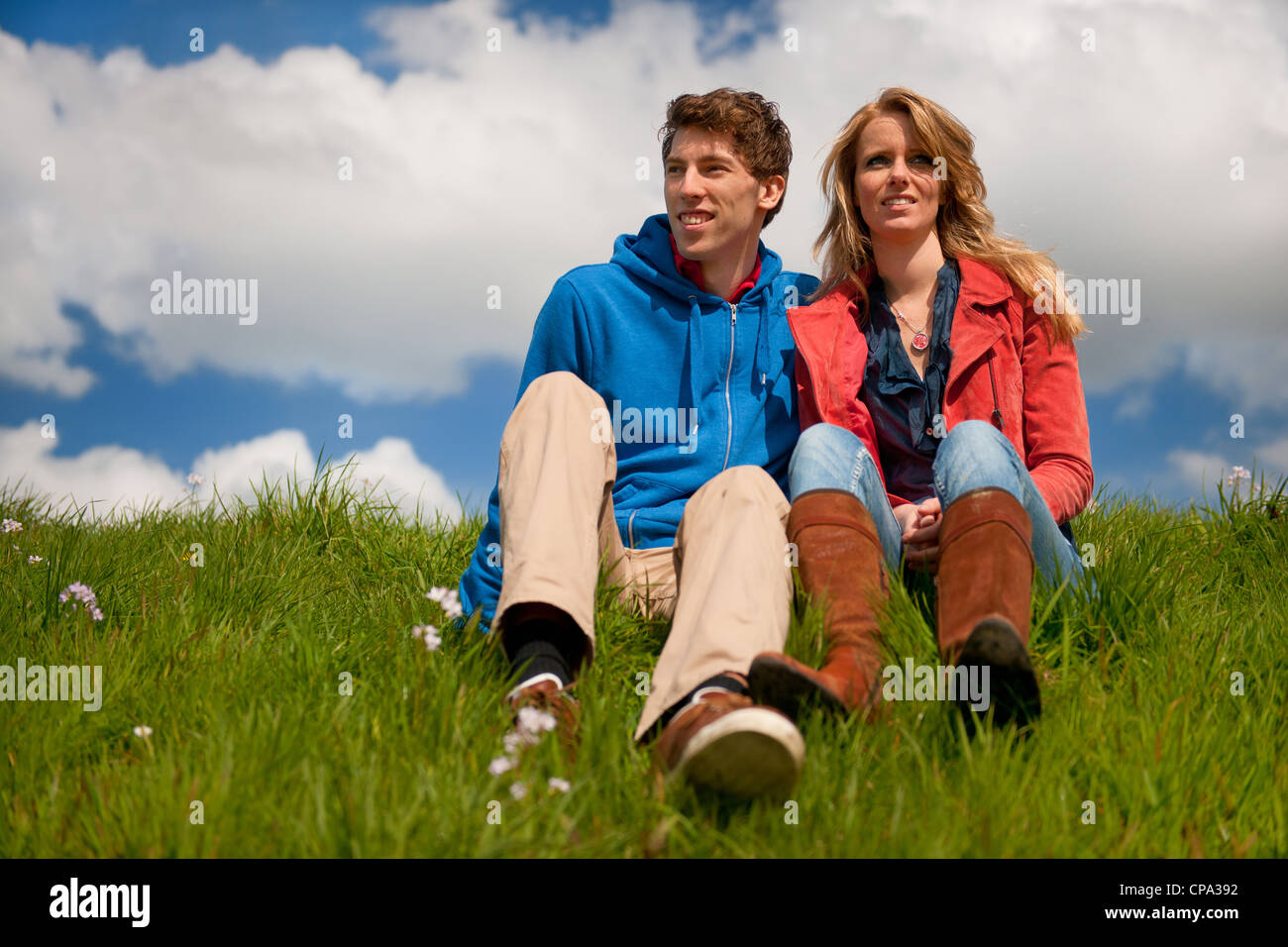 Young couple sitting in nature grass landscape Stock Photo - Alamy