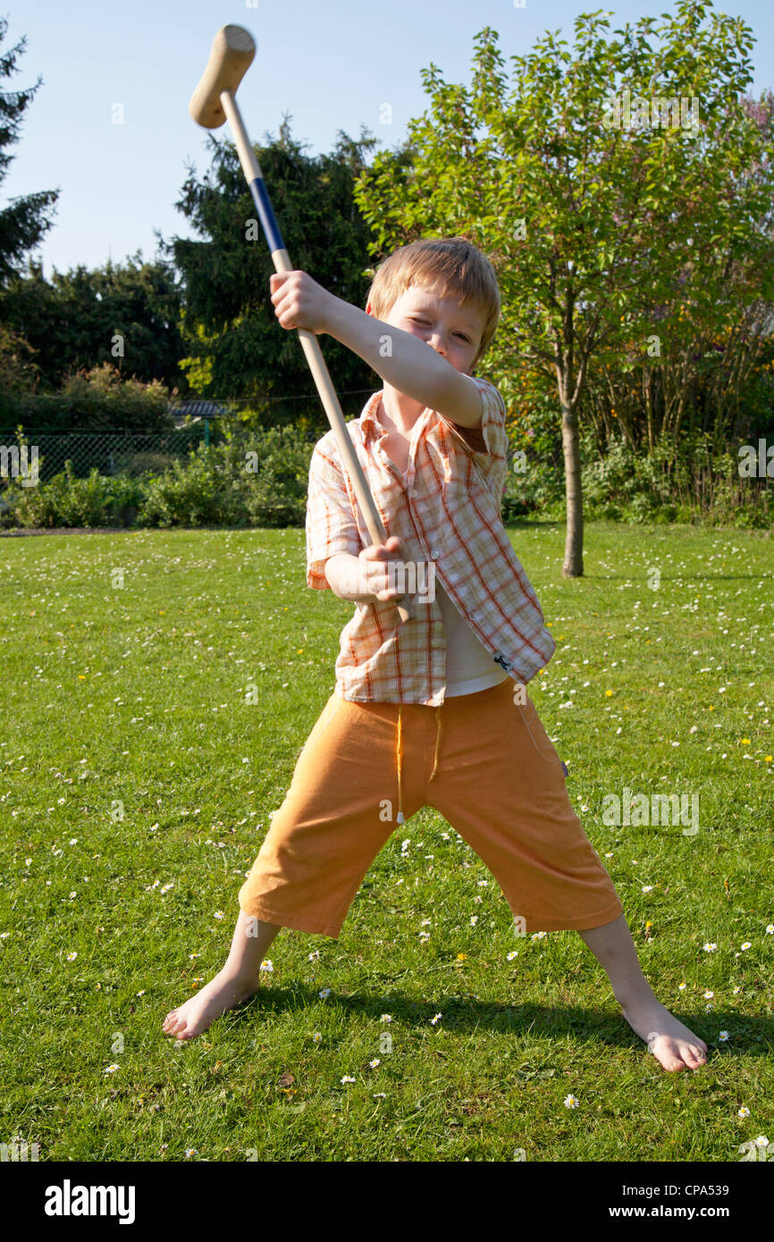 young boy hitting with a mallet Stock Photo - Alamy
