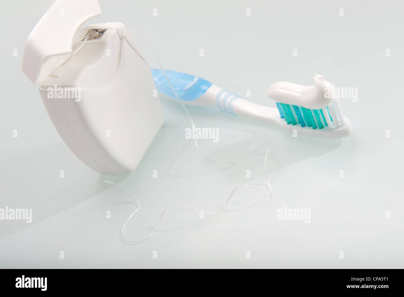 Toothbrush with toothpaste and dental floss on light background Stock ...