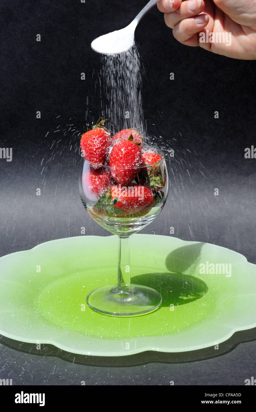 Sprinkling granulated sugar onto whole fresh strawberries Stock Photo ...
