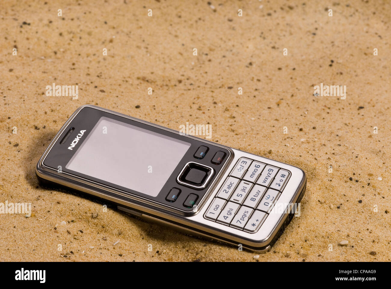Mobile phone dropped and laying in the sand at a beach. Lost misplaced ...
