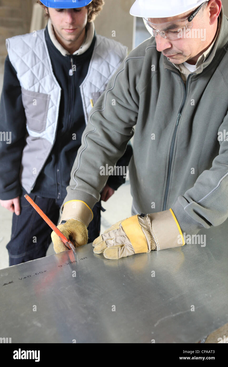 Engineer cutting sheet metal with apprentice Stock Photo - Alamy