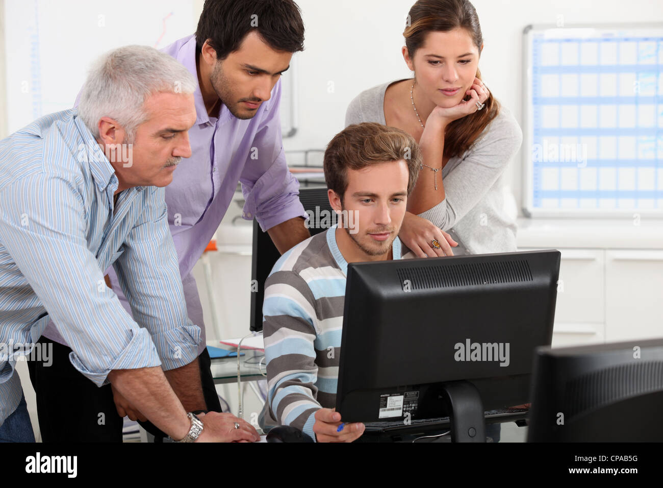 Colleagues looking at computer Stock Photo - Alamy