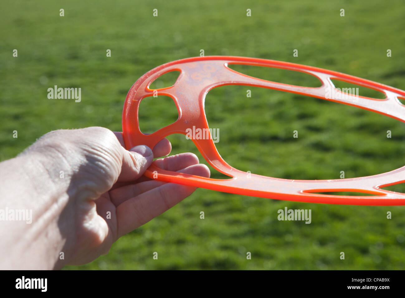 hand holding a rubber soft frisbee green grass Stock Photo - Alamy