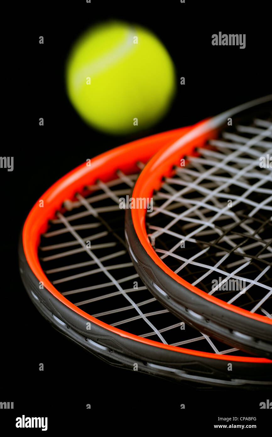 Tennis-ball and two racket on black background Stock Photo - Alamy