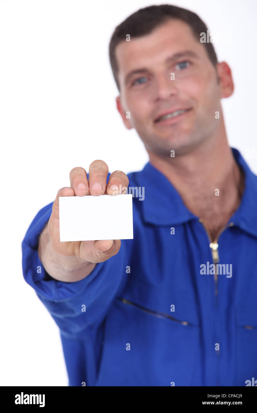 Man in blue overalls holding a business card left blank for your ...