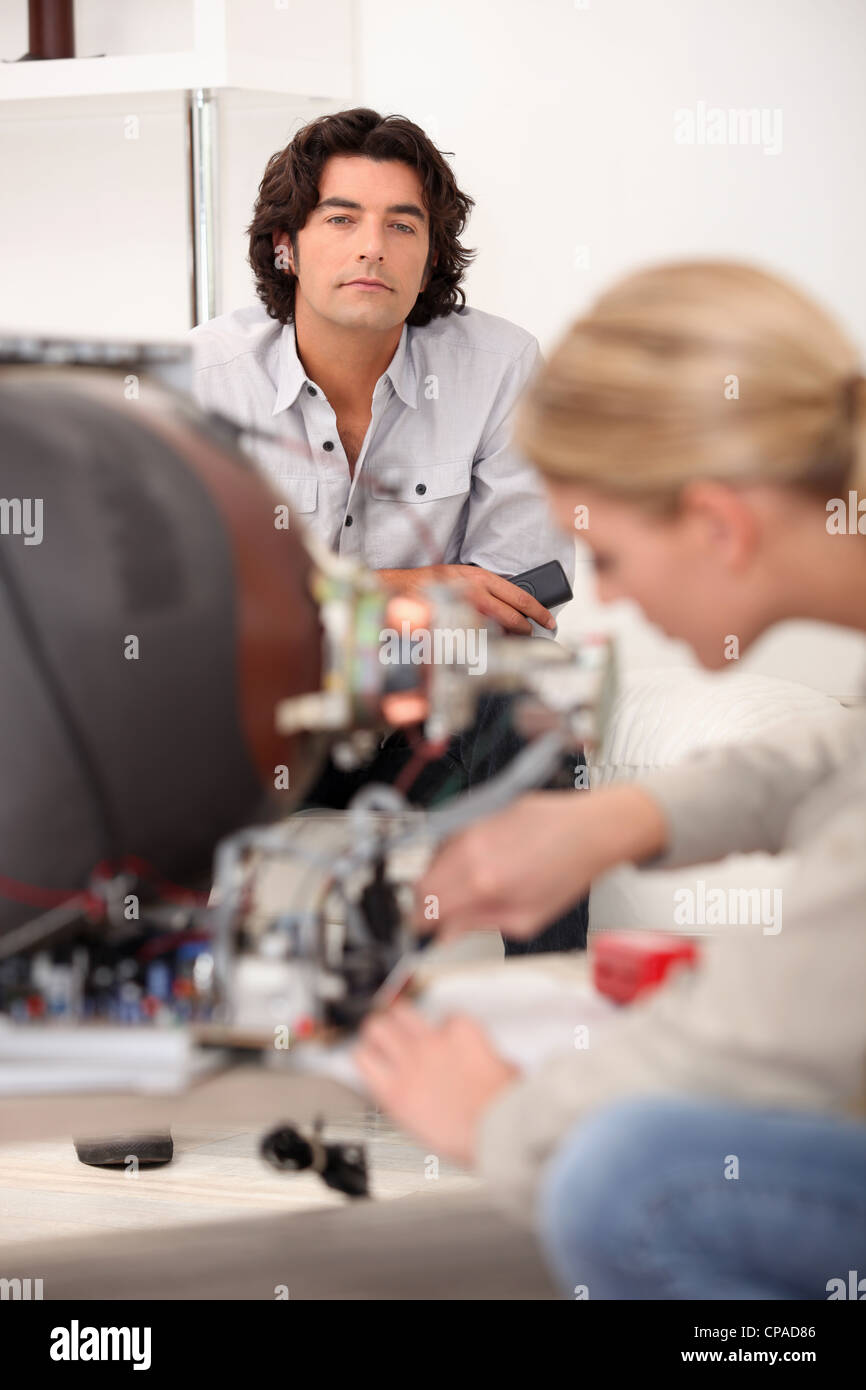 Man watching a woman repair a TV set Stock Photo - Alamy