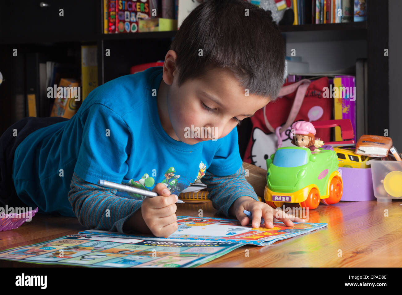 Boy,4 years old copies words colouring magazine at home Stock Photo - Alamy