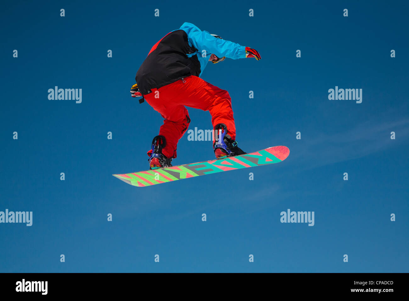 A free-style boarder executes a jump and twist against a clear blue sky ...