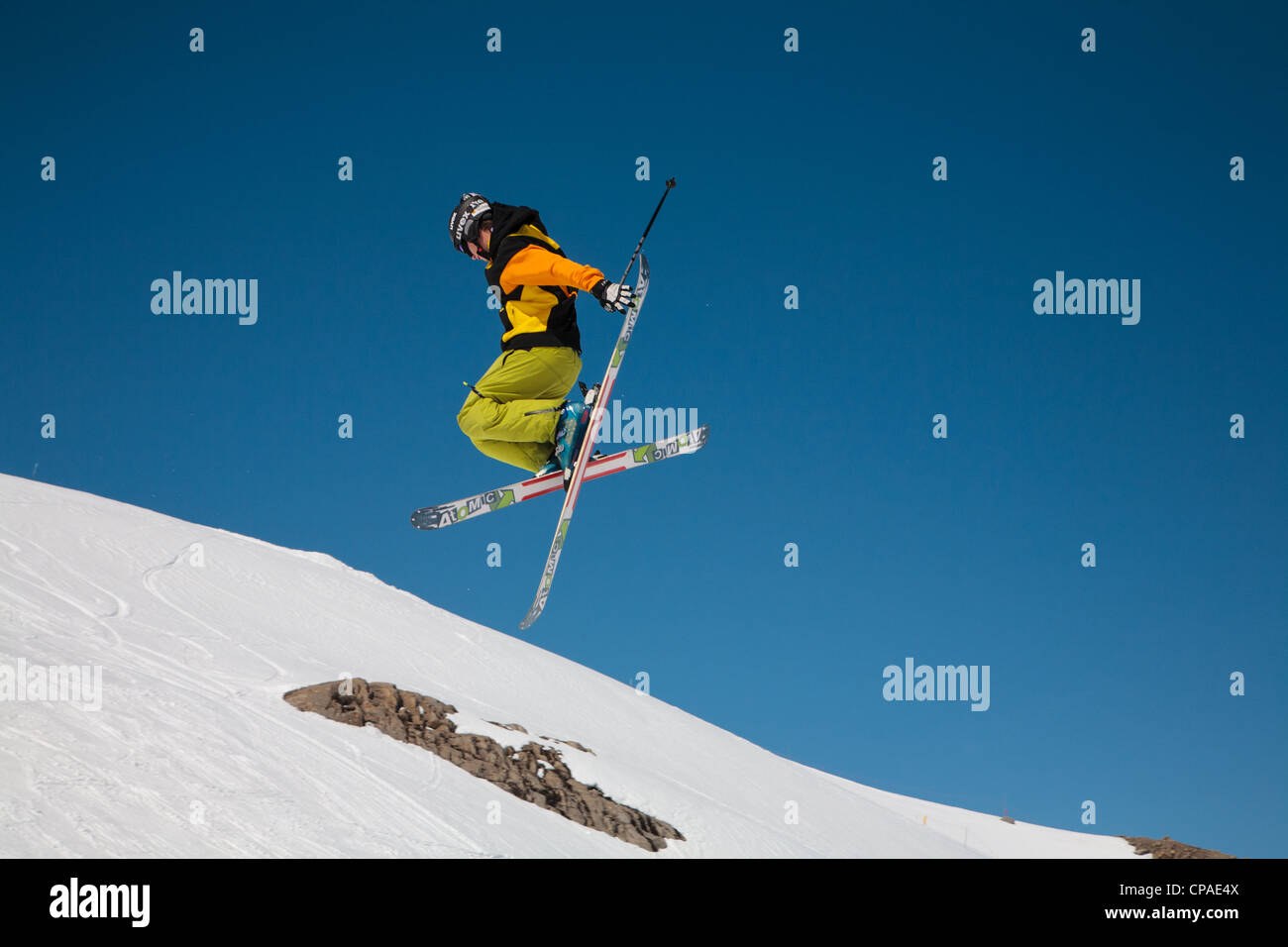 A free-style skier executes a jump and mid-air twist against a clear ...