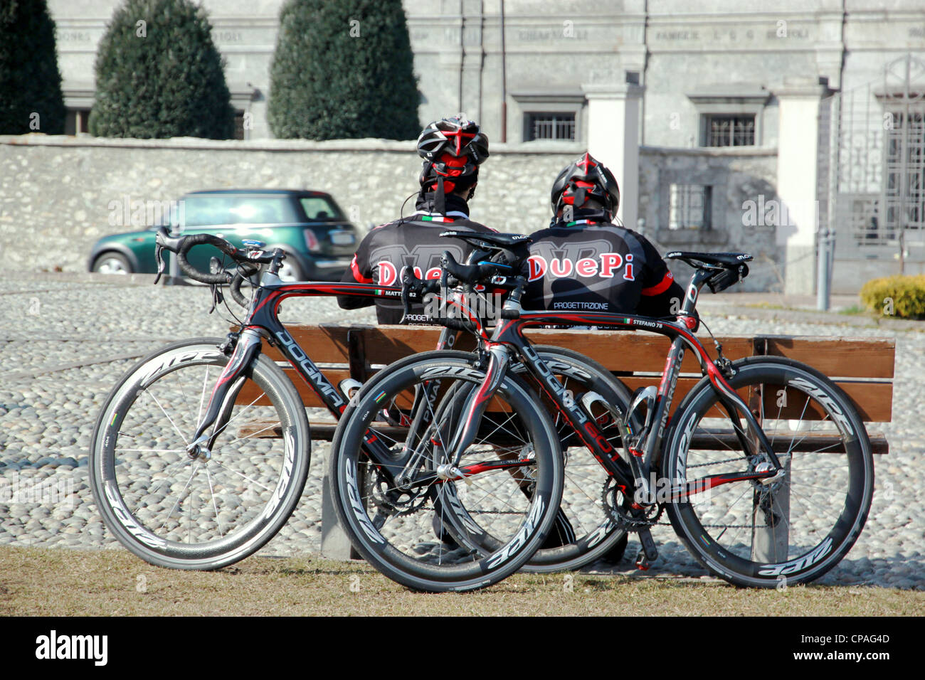 Two cyclists having a break on a bench Stock Photo - Alamy