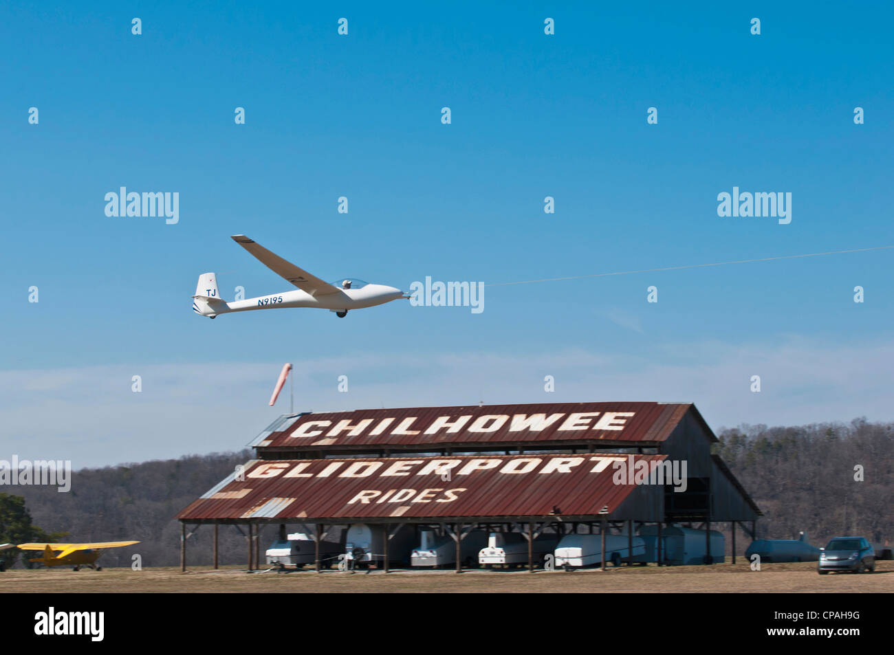 USA, TN, Chilhowee Gliderport. Fiberglass sailplane on tow over barn ...