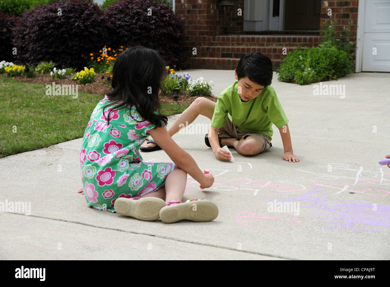 Children playing with chalk in the driveway Stock Photo - Alamy