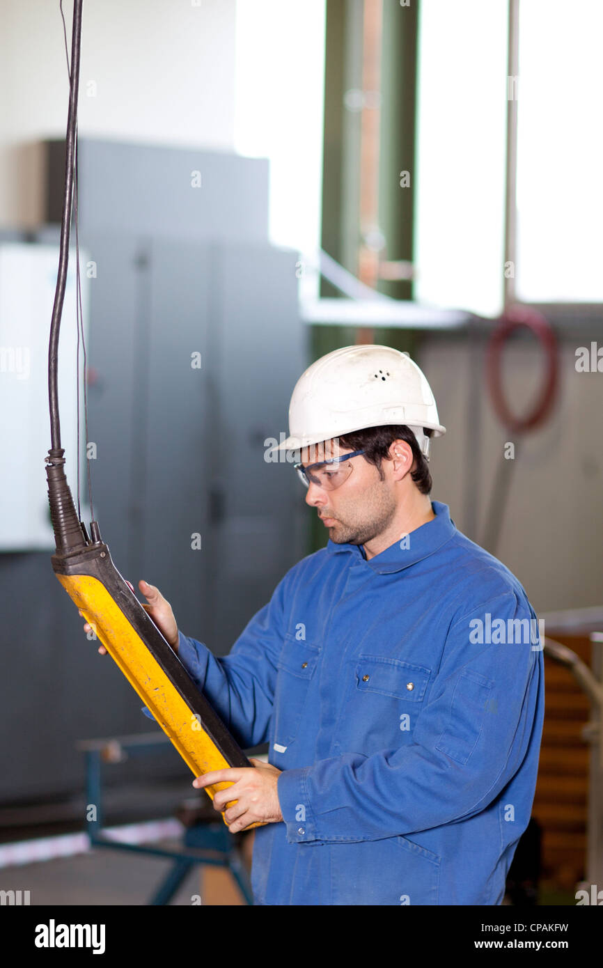 Blue collar worker using a crane in factory Stock Photo - Alamy