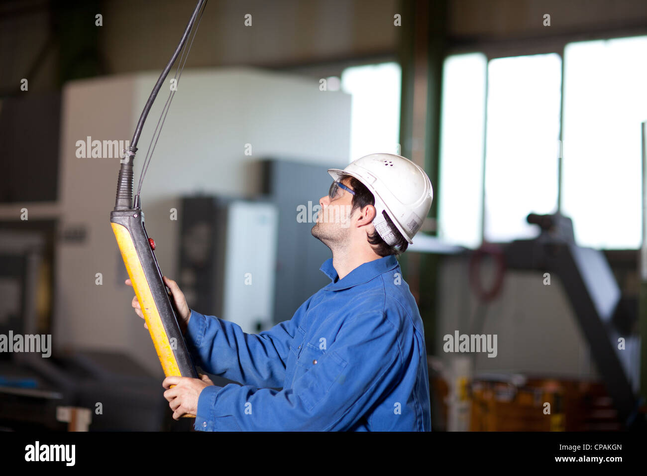 Blue collar worker using a crane in factory Stock Photo - Alamy