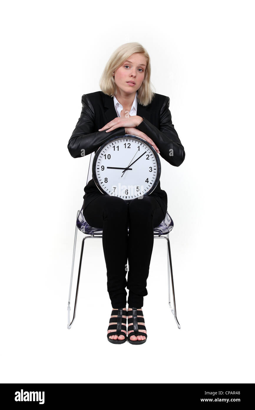 Woman sitting with a clock on her knees Stock Photo - Alamy