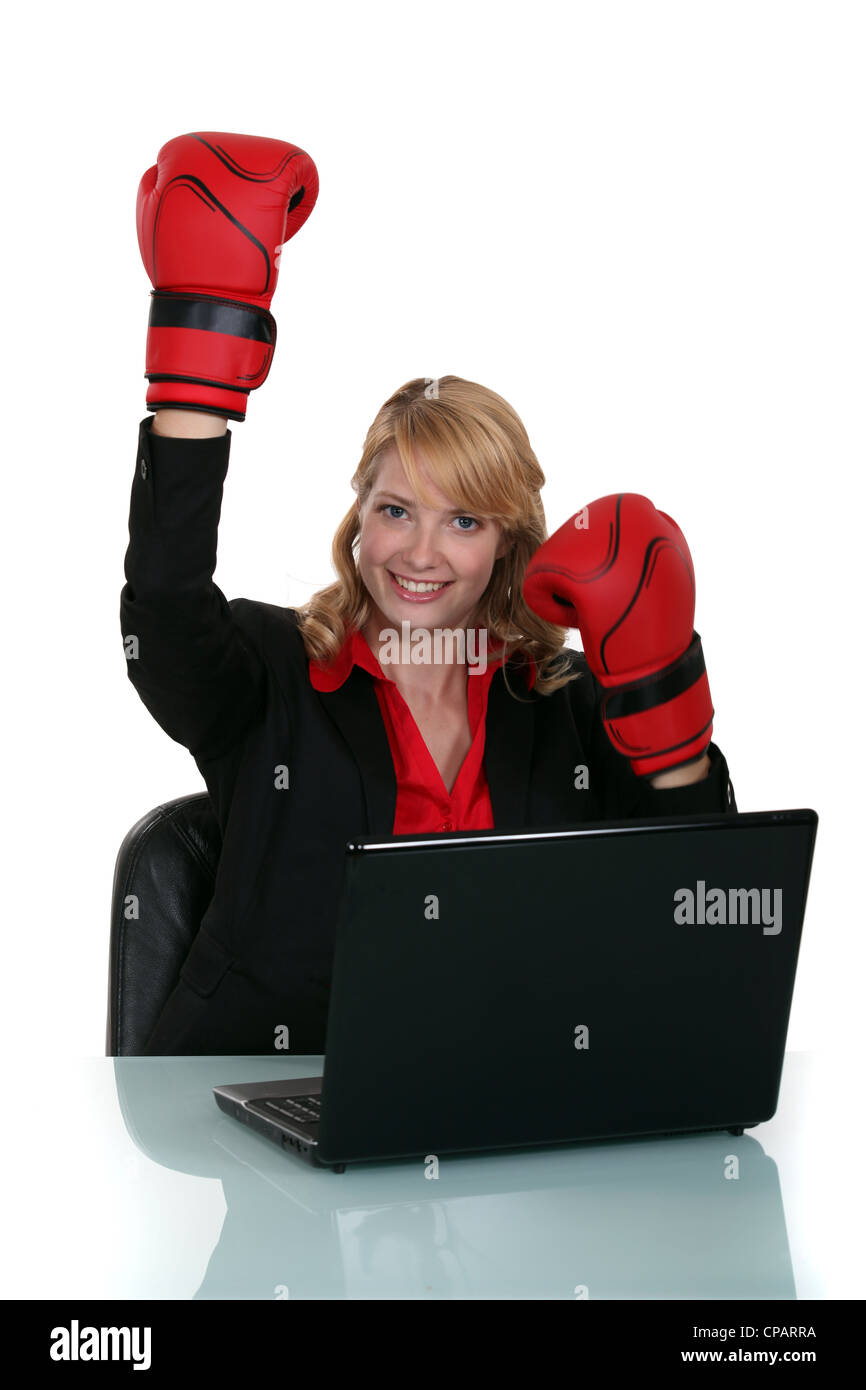 Woman wearing boxing gloves whilst sat at desk Stock Photo - Alamy
