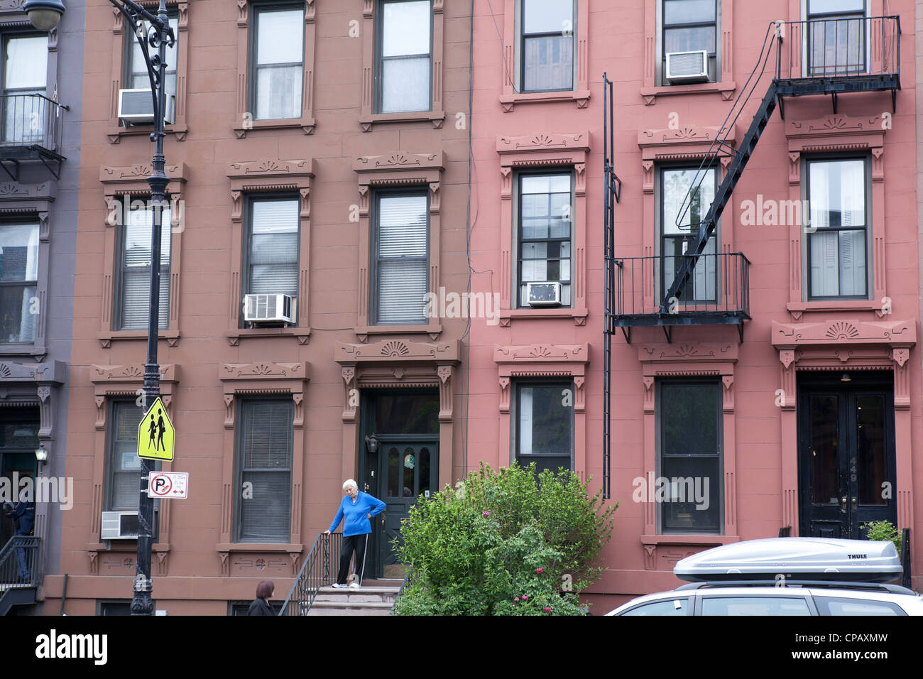 A woman stands on the stoop of a brownstone building in Brooklyn, New ...