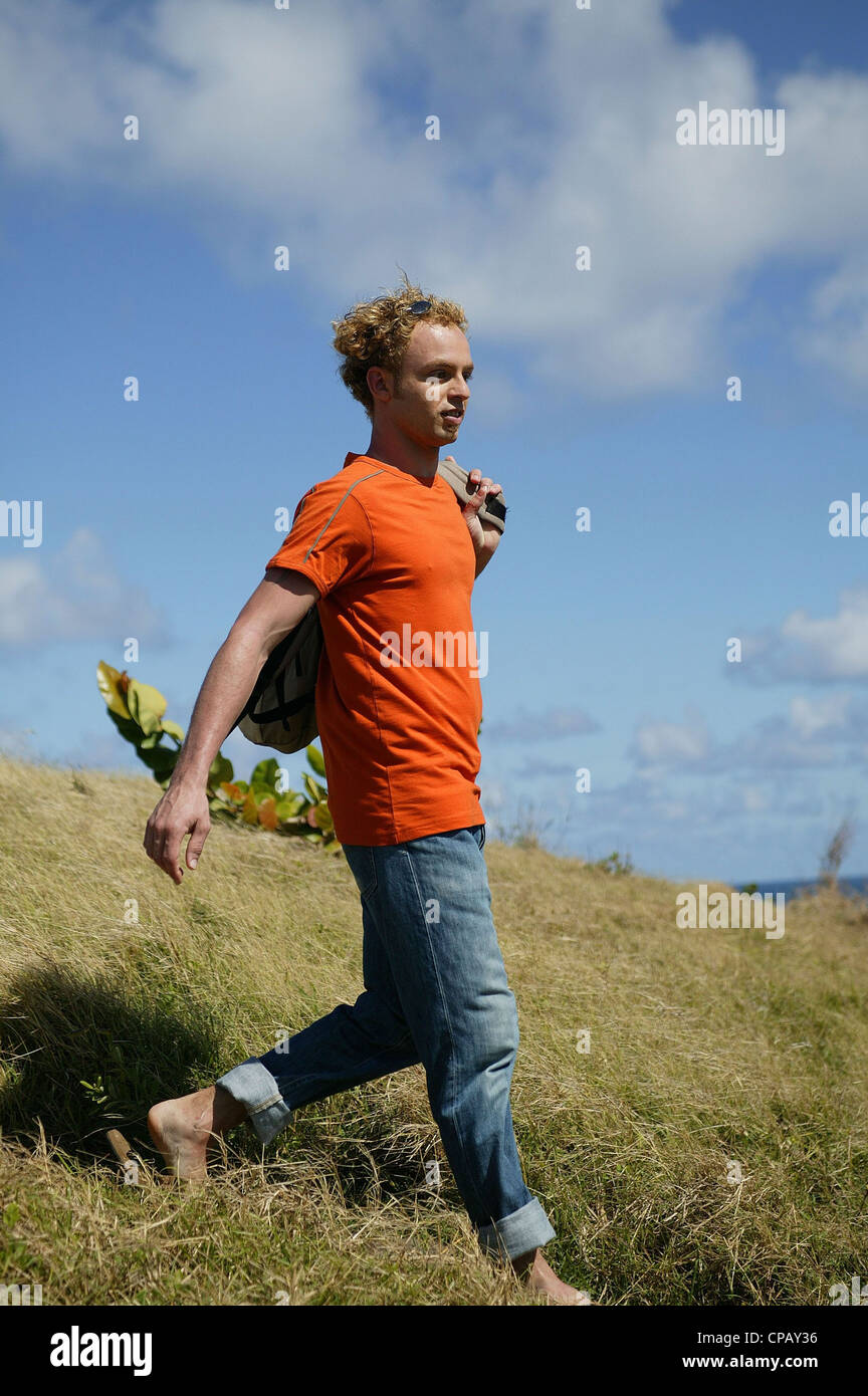 Man walking through field with backpack Stock Photo - Alamy