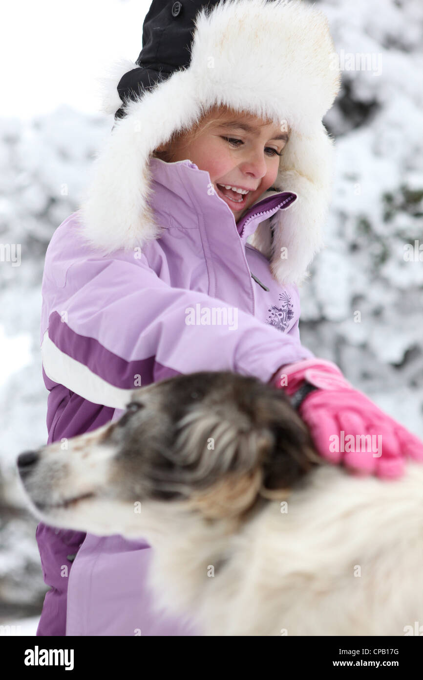 Little girl petting dog in the snow Stock Photo - Alamy