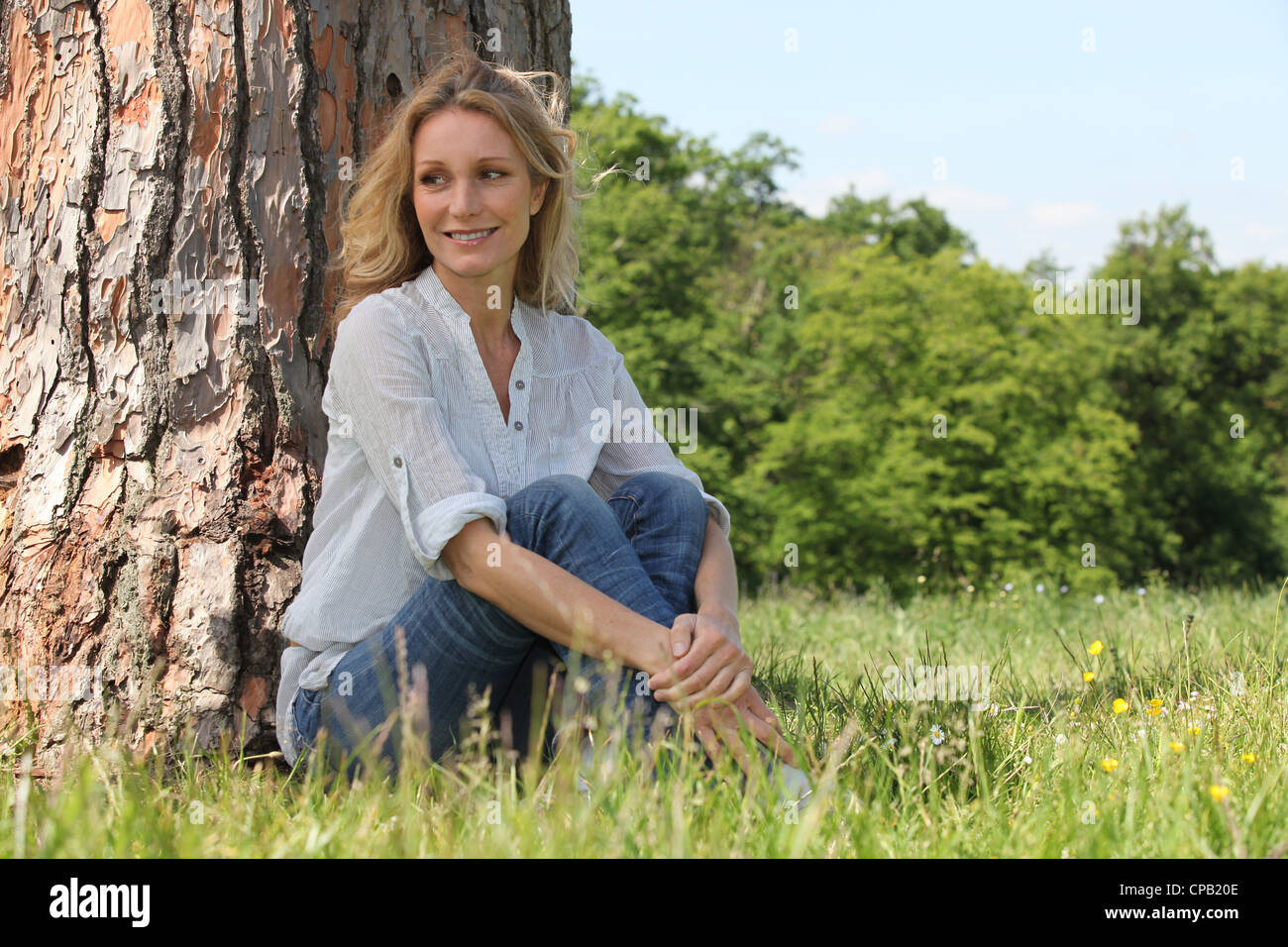 woman sitting against tree Stock Photo - Alamy