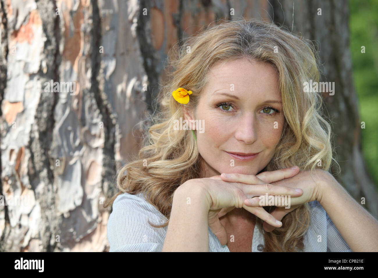 Portrait of woman in front of tree trunk Stock Photo - Alamy