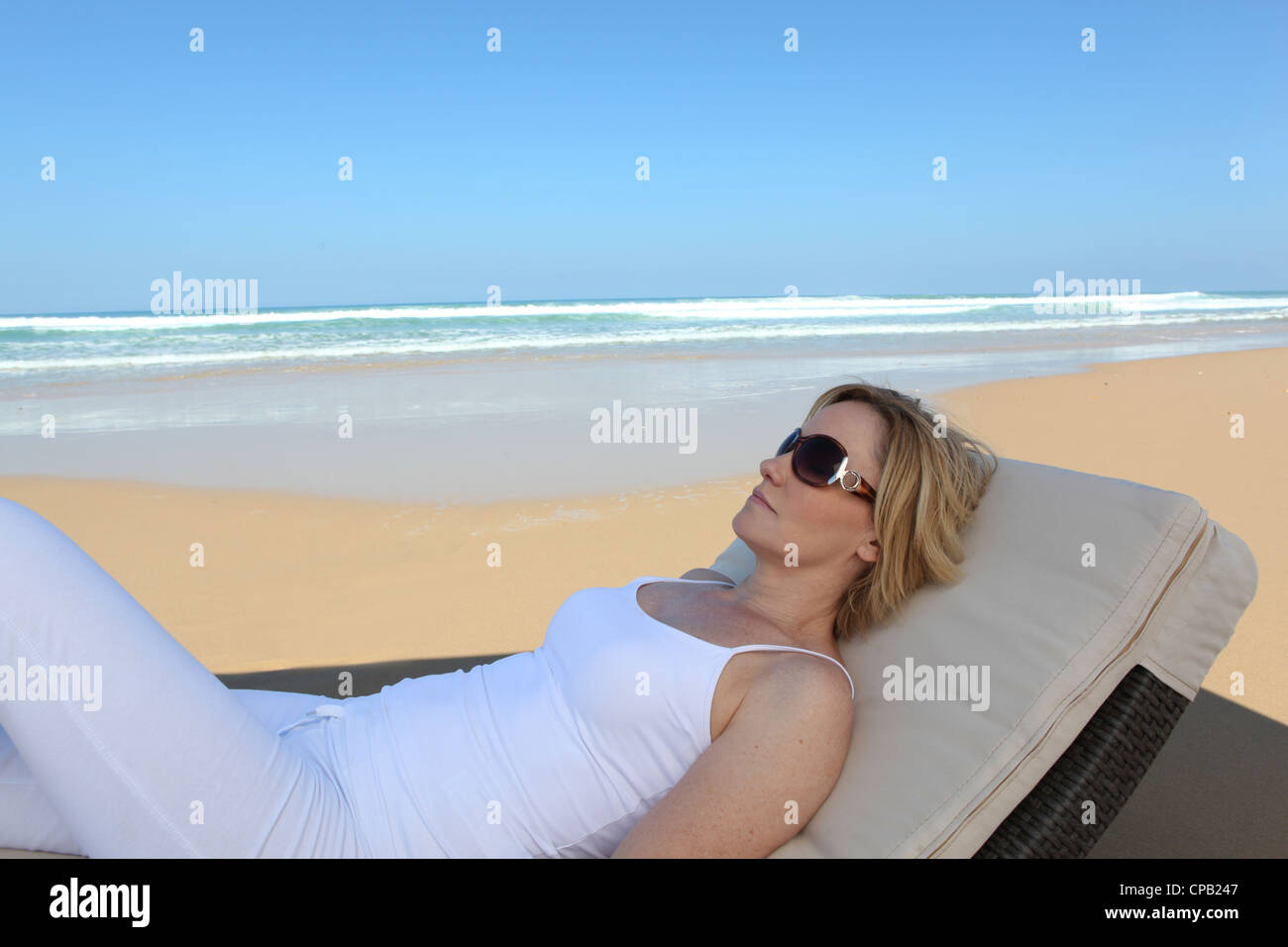 Woman lying on a lounge chair at the beach Stock Photo - Alamy
